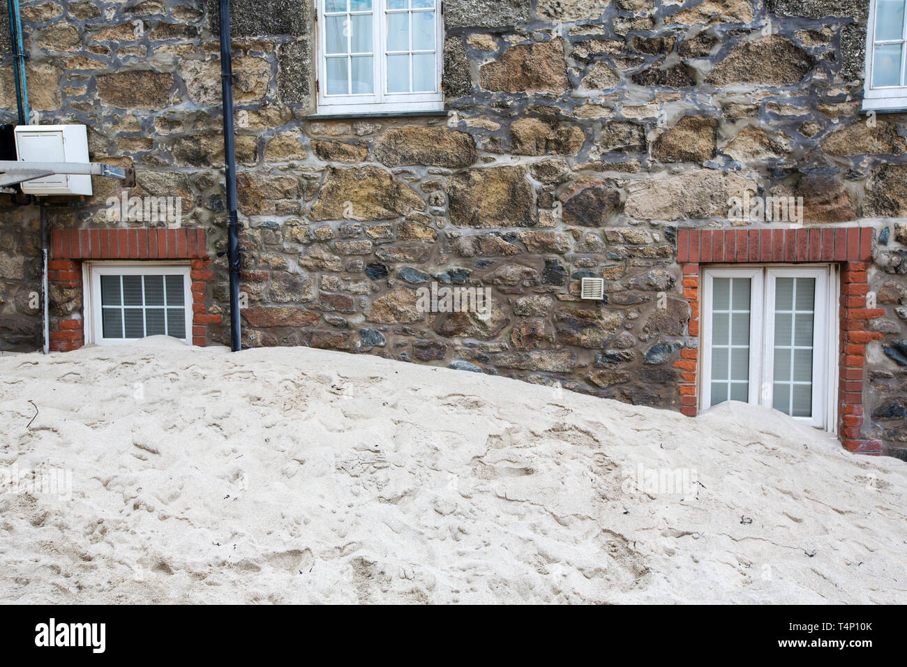 Sand pushed up against houses from Porthmeor beach in St Ives by a ...