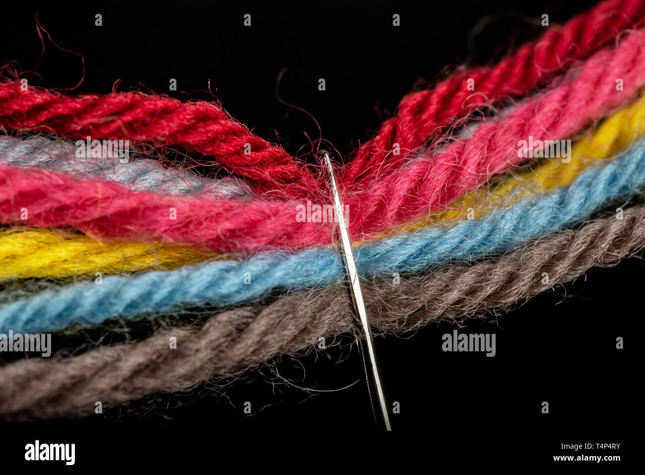 On a black background, several bright multicolored woolen threads are ...