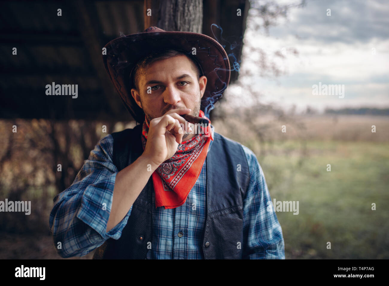 Brutal cowboy smokes a cigar, texas ranch on background, western ...