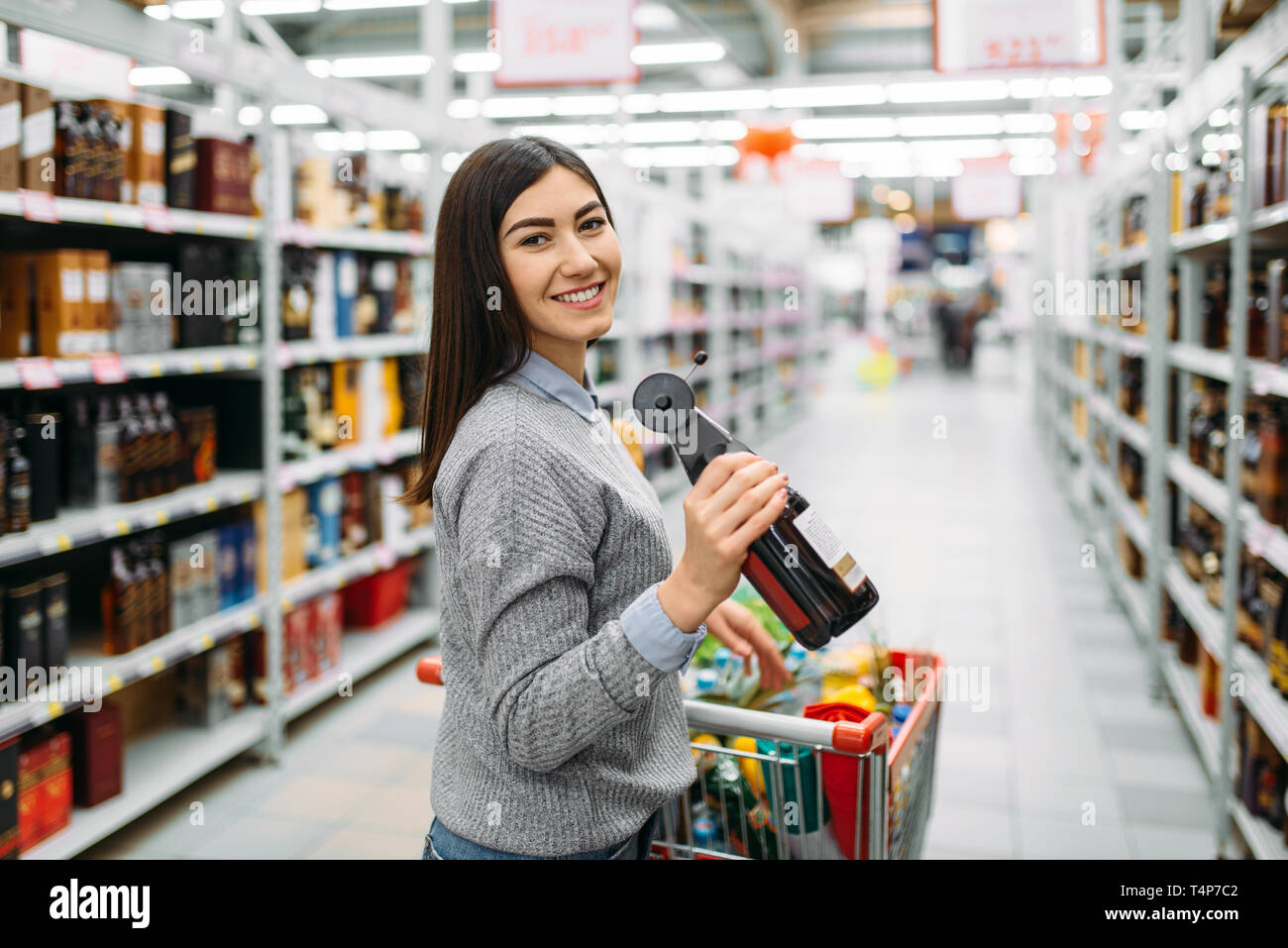 Woman with bottle of alcoholic beverage in supermarket, alcohol drinks ...