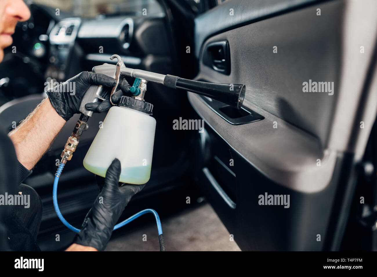 Carwash service, male worker in gloves using special spray ...