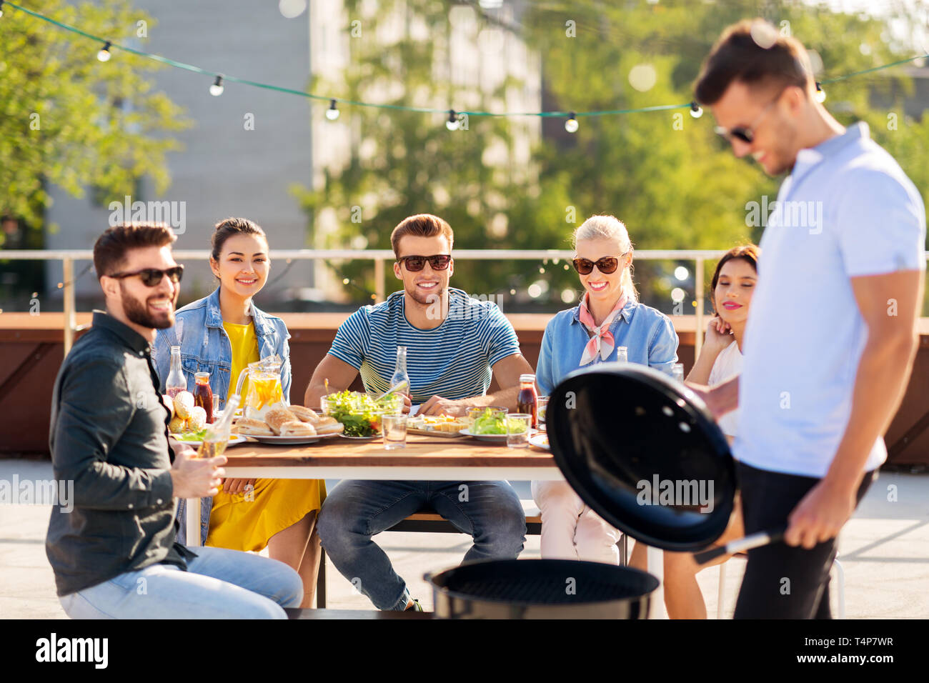 leisure and people concept - happy man grilling on bbq and friends at ...