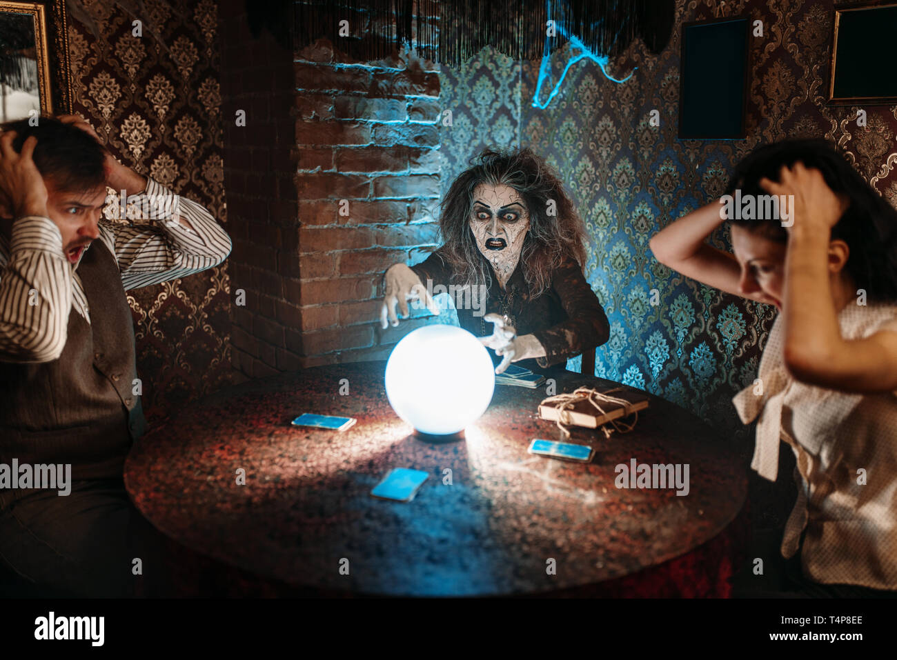 Witch reads scary magic spell over a crystal ball, young people in ...