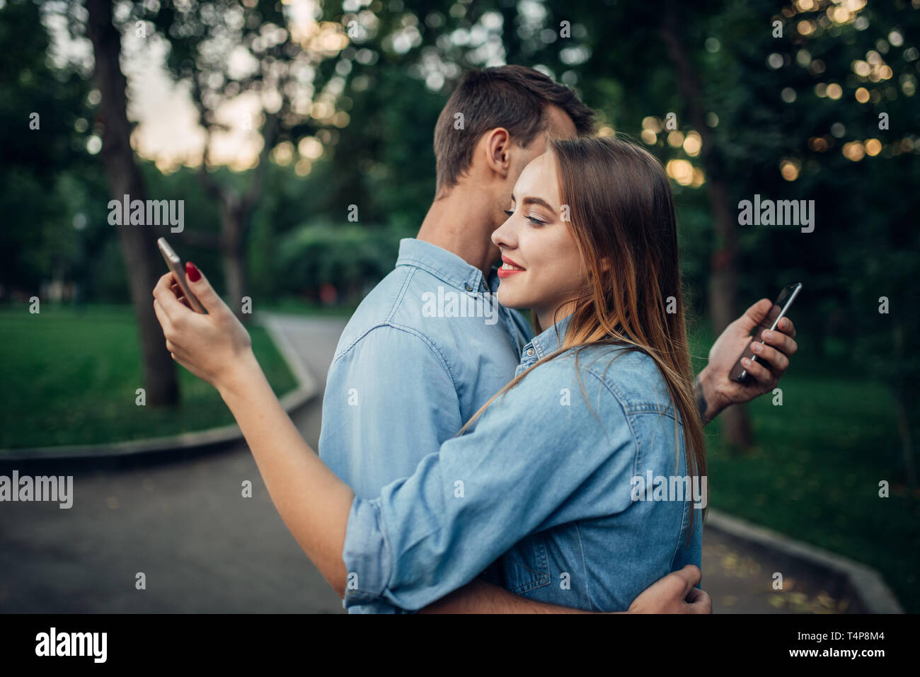 Phone addiction, addict couple hugs and using gadgets in summer park ...
