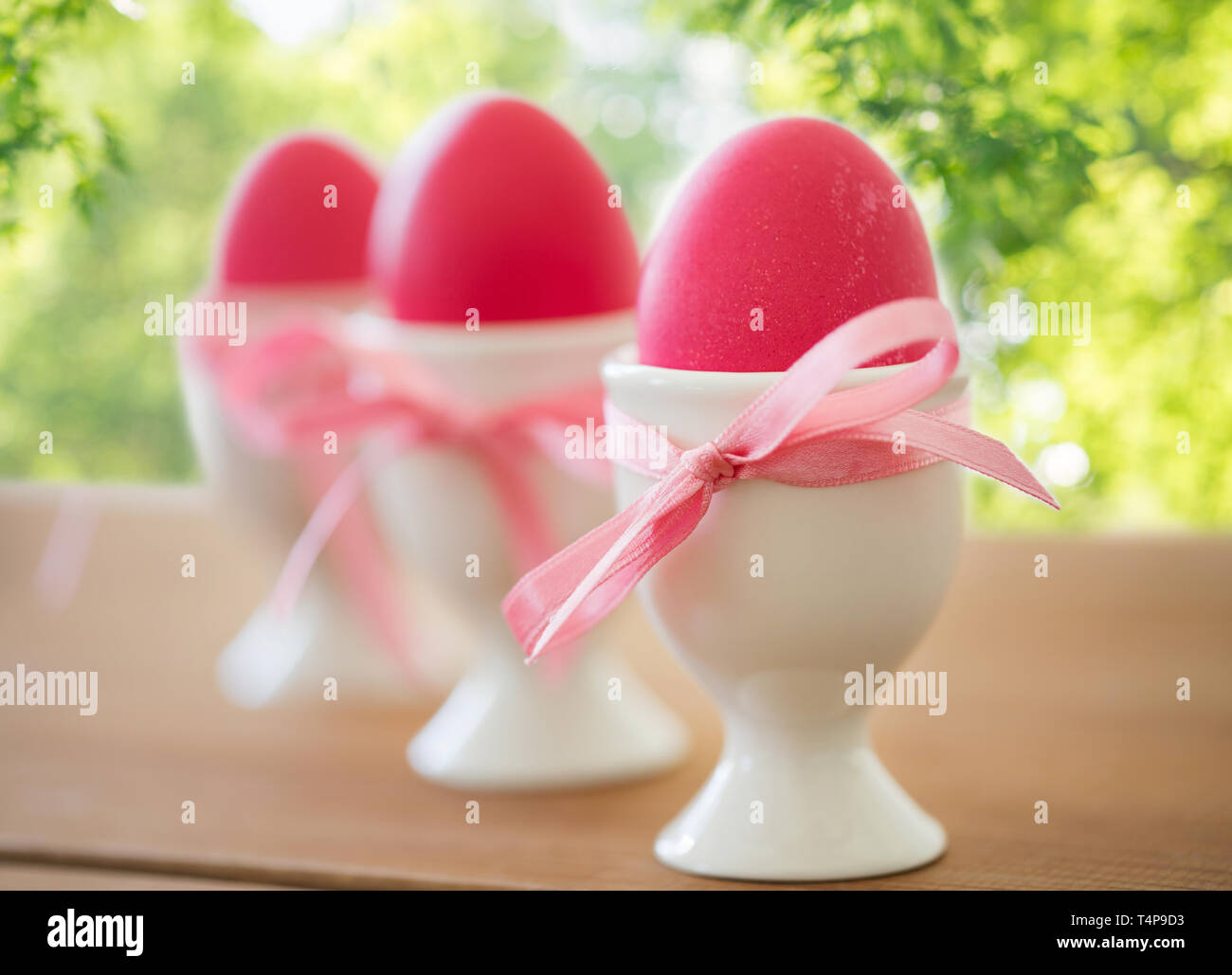 easter and holidays concept - pink colored eggs in ceramic cup holders ...