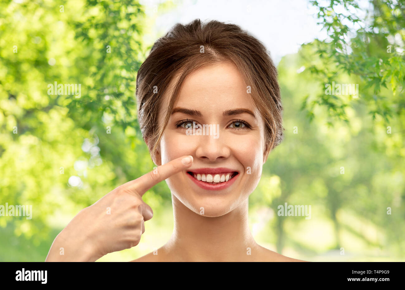 beauty, people and rhinoplasty concept - beautiful young woman pointing ...