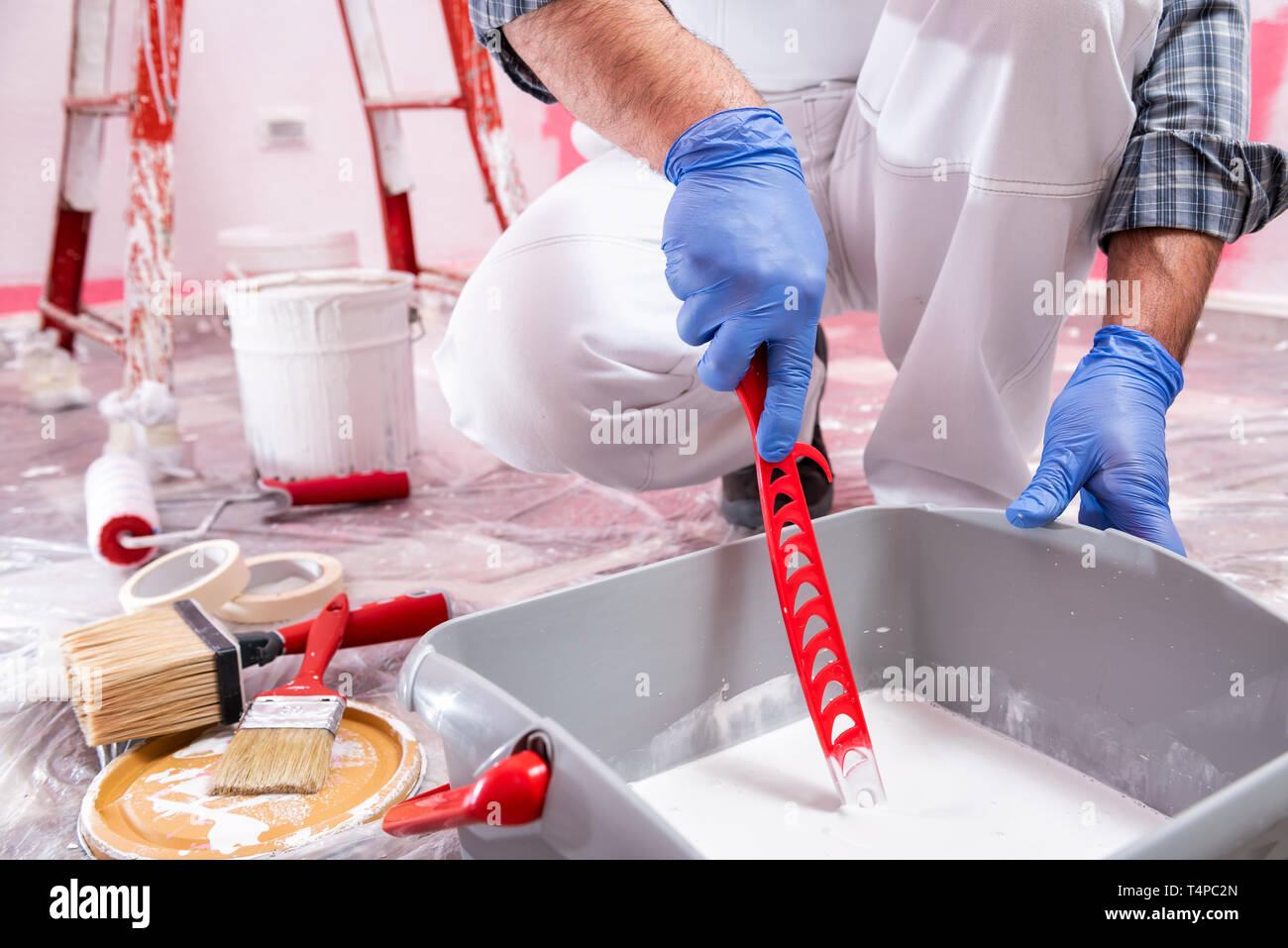 Caucasian house painter worker in white overalls, prepare the white ...