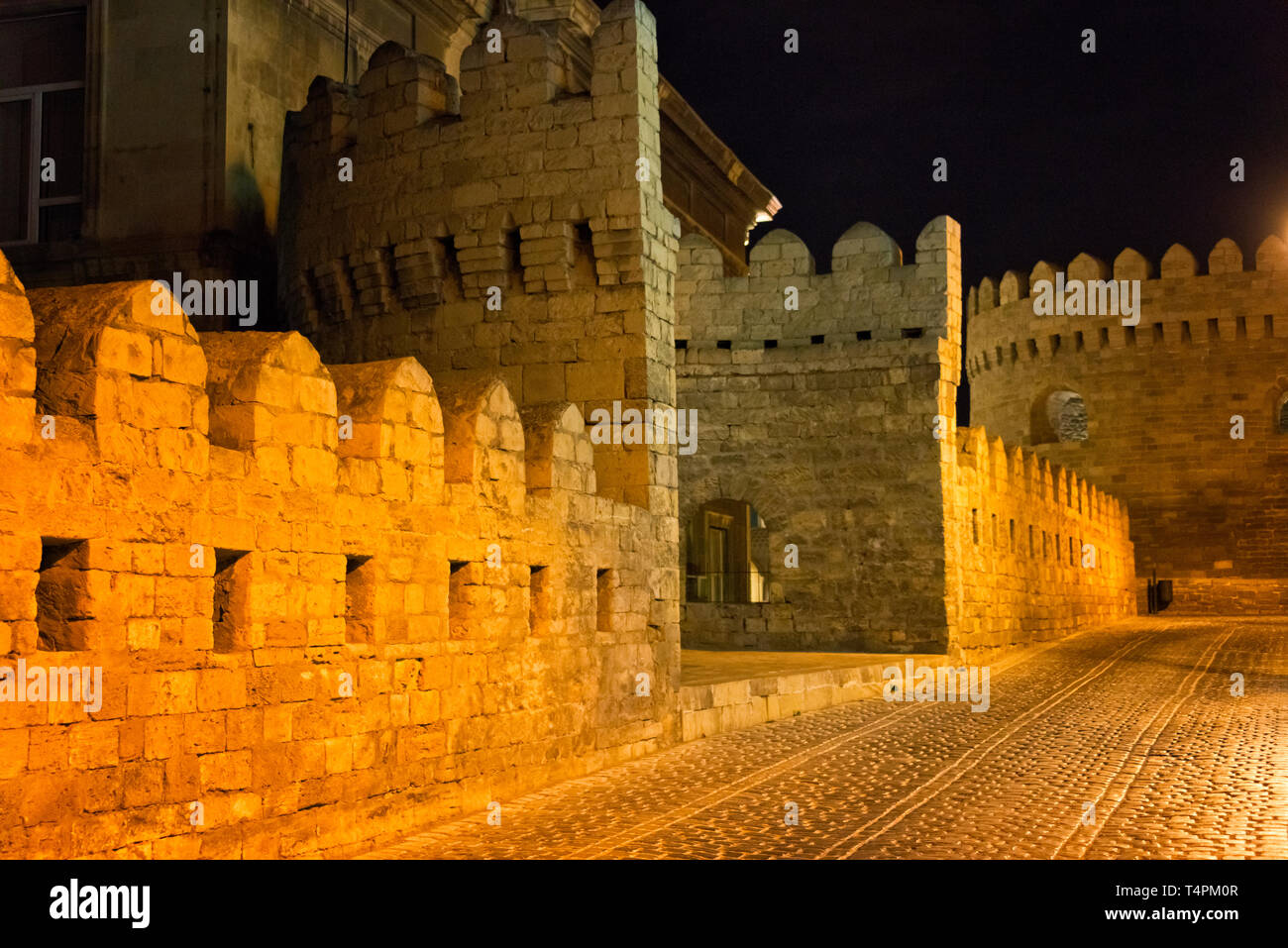 Old city wall and cobblestone street in the Inner City of Baku at night ...