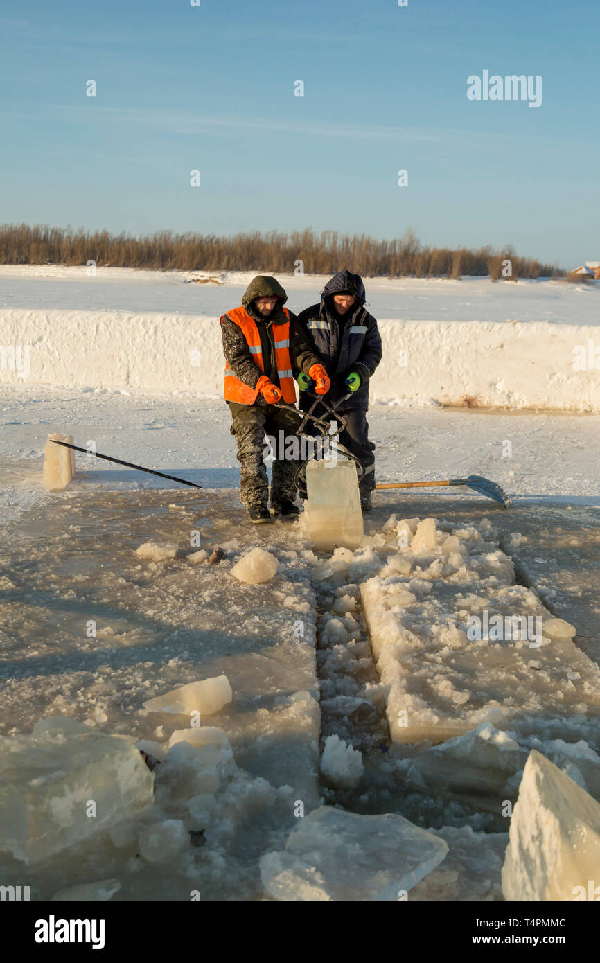 Workers pull ice block out of the hole with steel tongs Stock Photo - Alamy