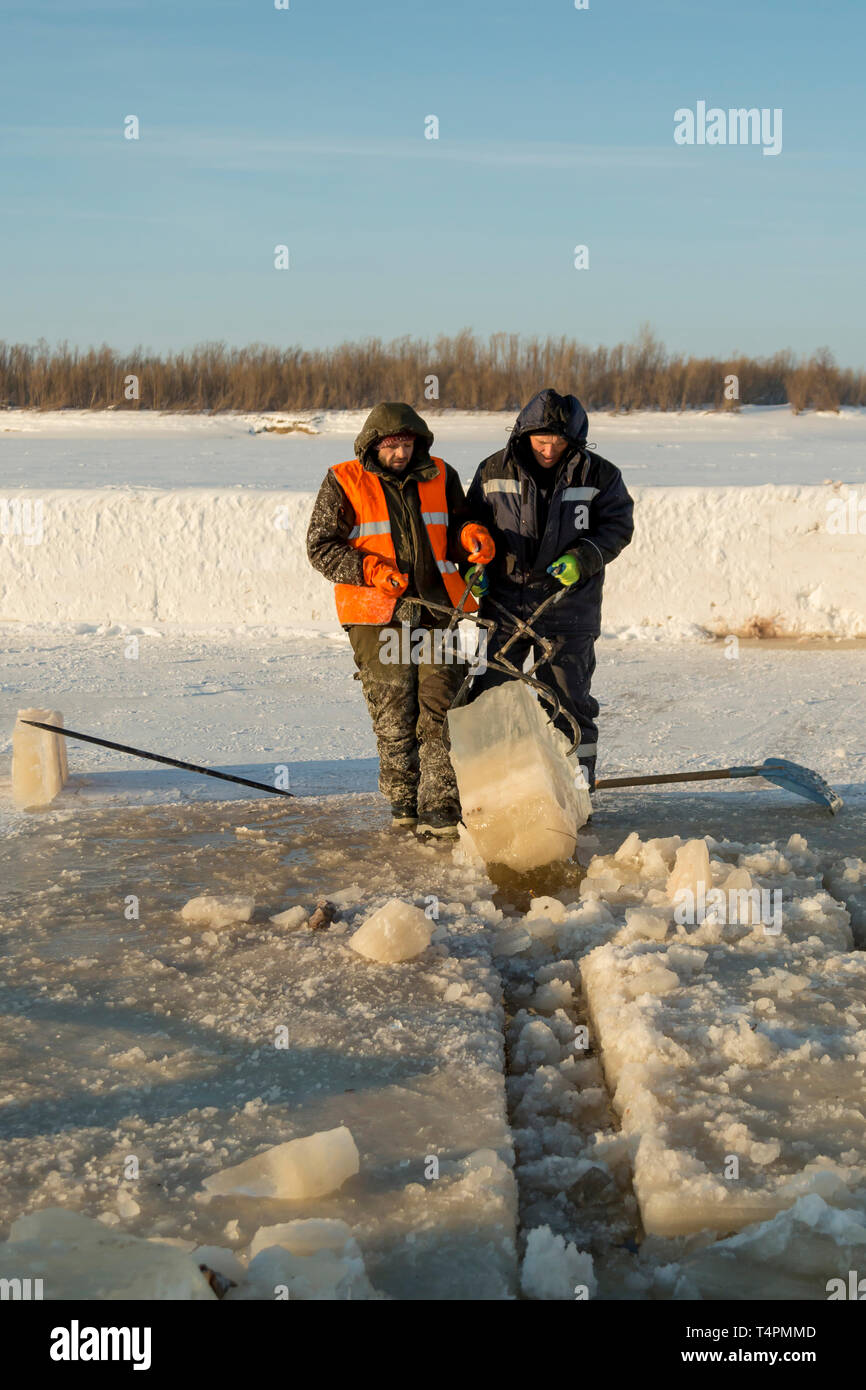 Workers pull ice block out of the hole with steel tongs Stock Photo - Alamy