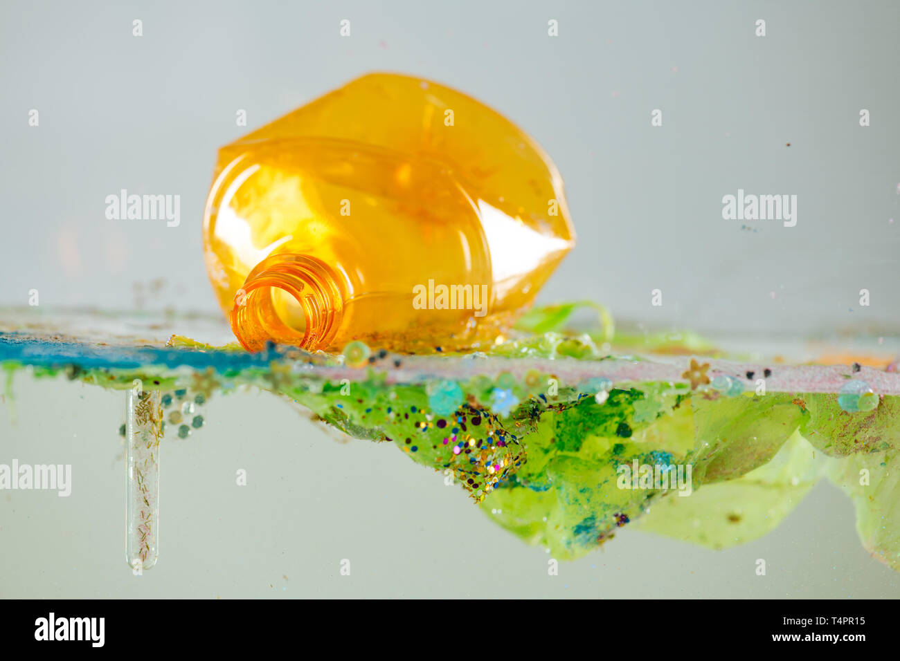 Dirty water. Crumpled orange plastic bottle floating on the water ...
