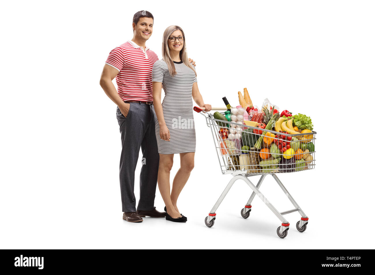 Young man and woman posing with a full shopping cart isolated on white ...