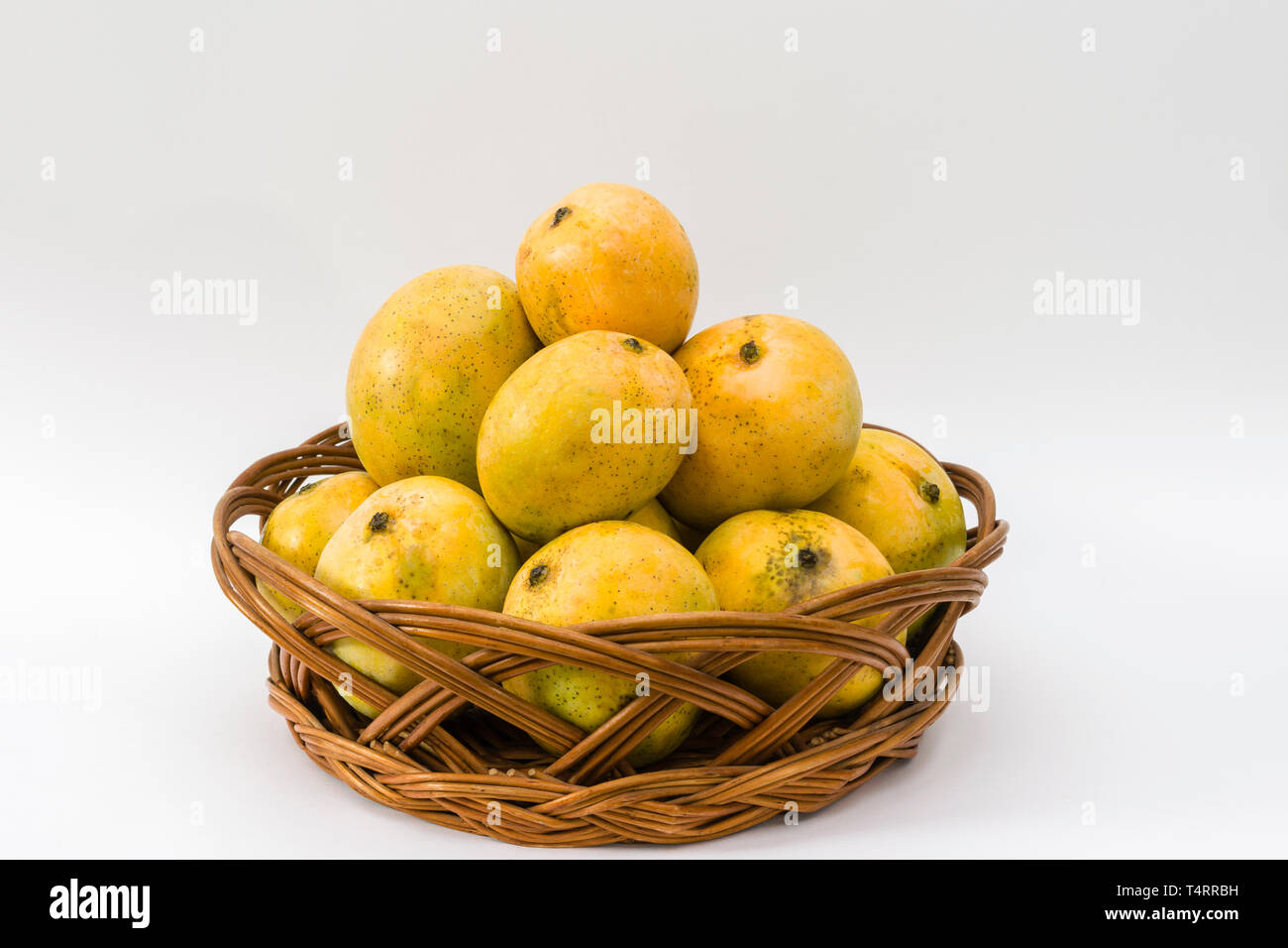 A basket of Moovandan mangoes (Mangifera indica) on a white background ...