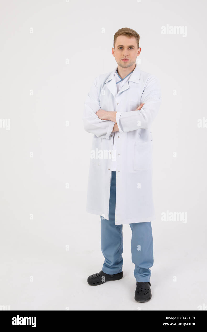 Young sympathetic doctor stands isolated on a white background dressed ...