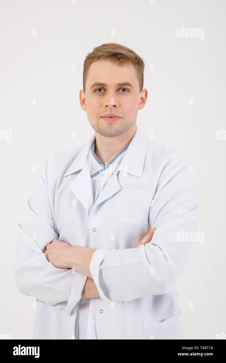 Young sympathetic doctor stands isolated on a white background dressed ...