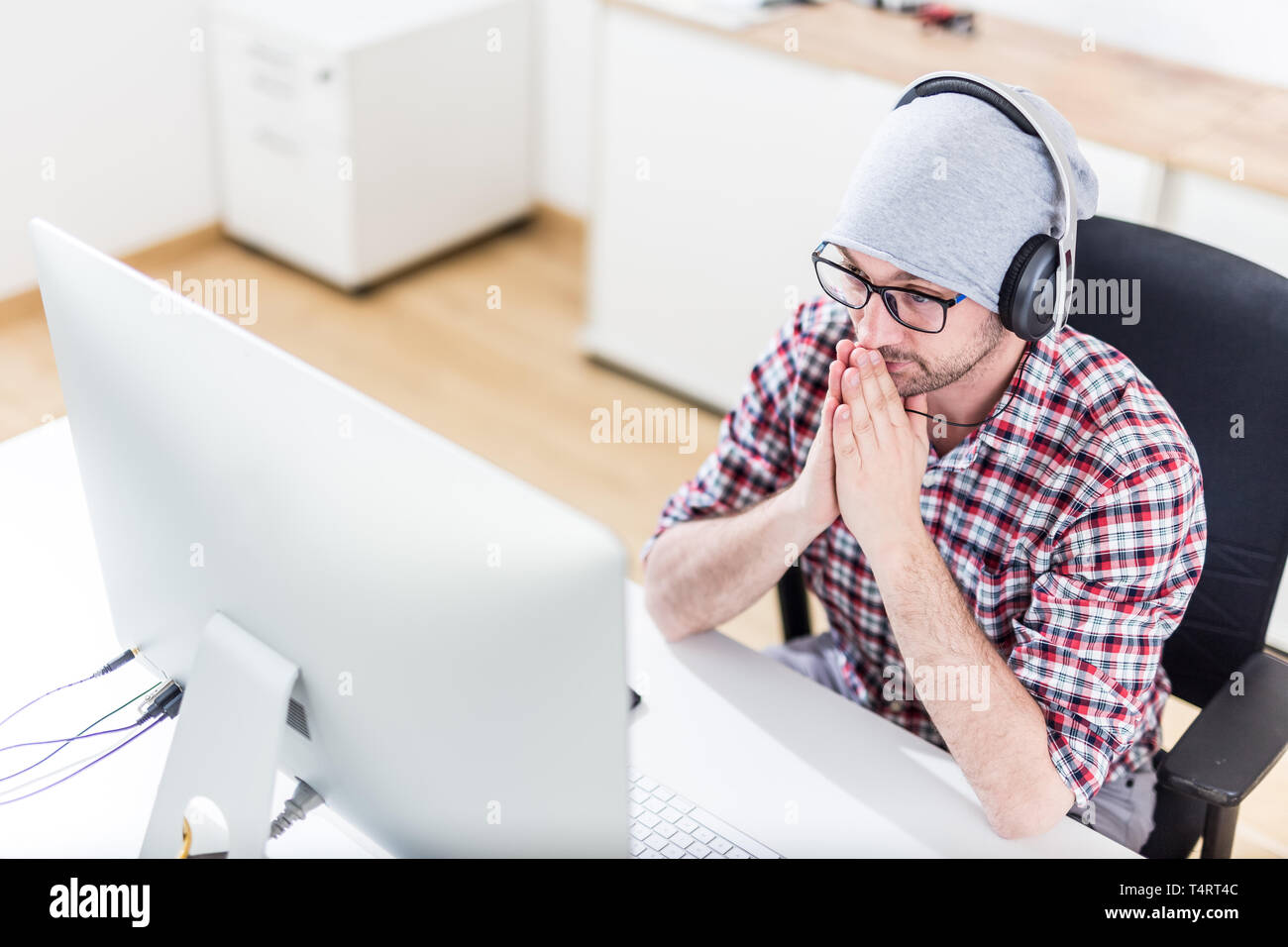Man with headphones under stress looking at desktop computer monitor ...