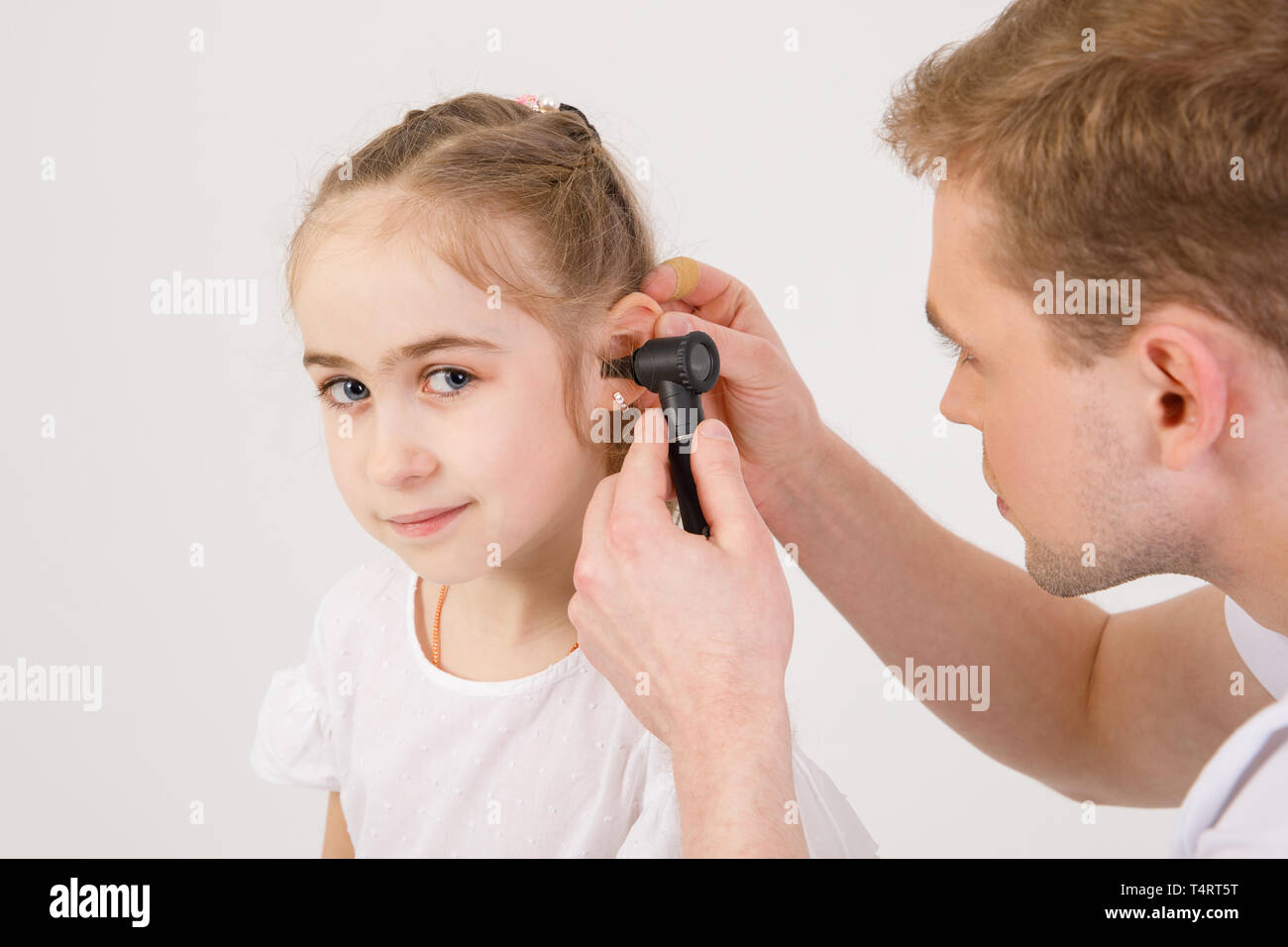 The young sympathetic otolaryngologist examines the ears of a girl - a ...
