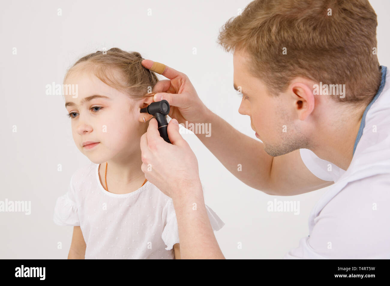The young sympathetic otolaryngologist examines the ears of a girl - a ...