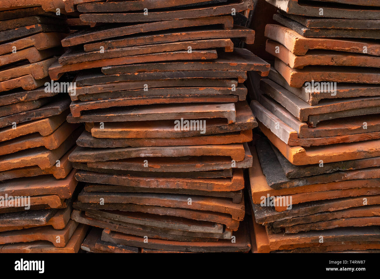 A close up of a pile of red clay roofing tiles stacked on top of each ...