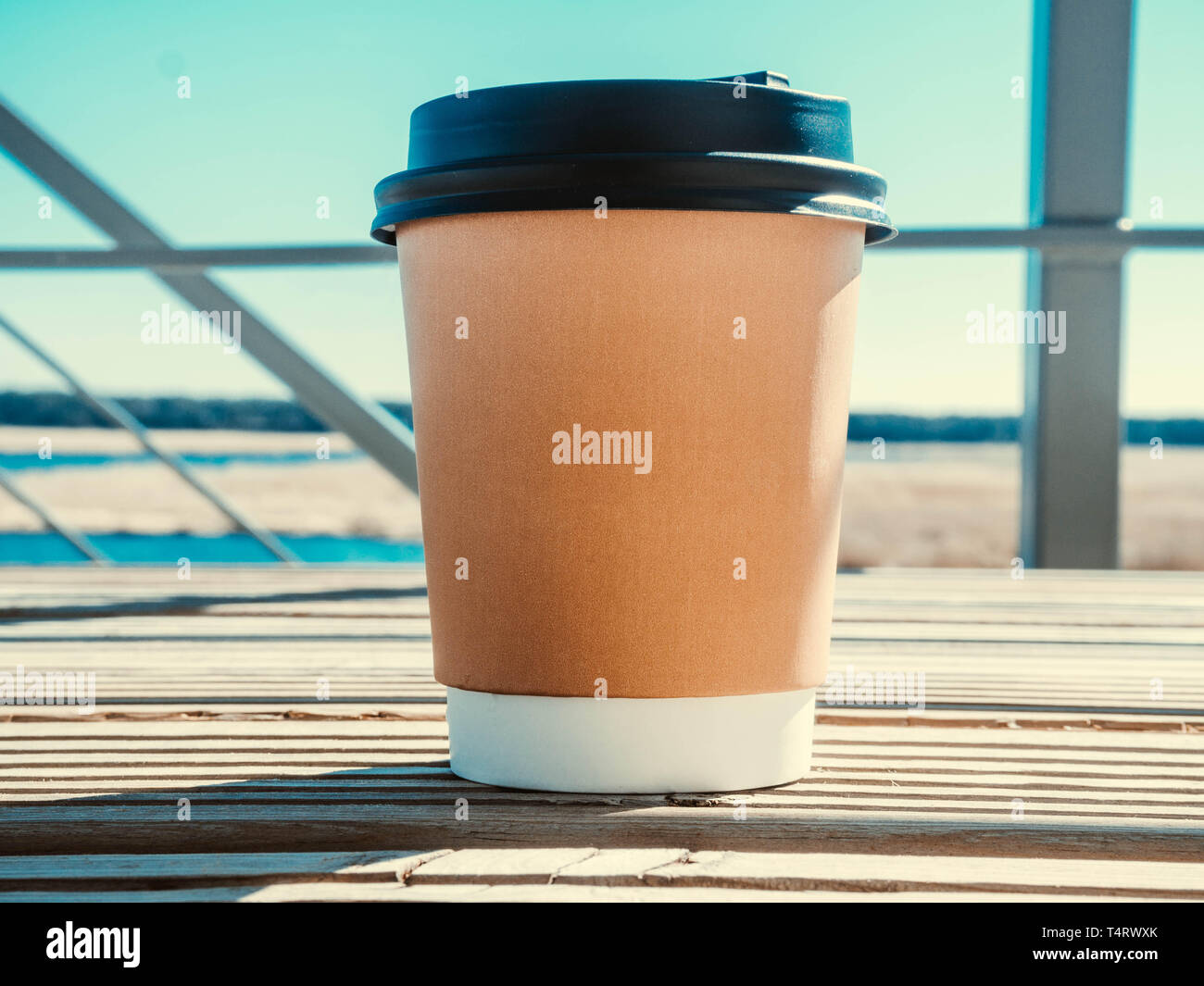 Cup of coffee to go on the wooden table. Street coffee, blurred ...