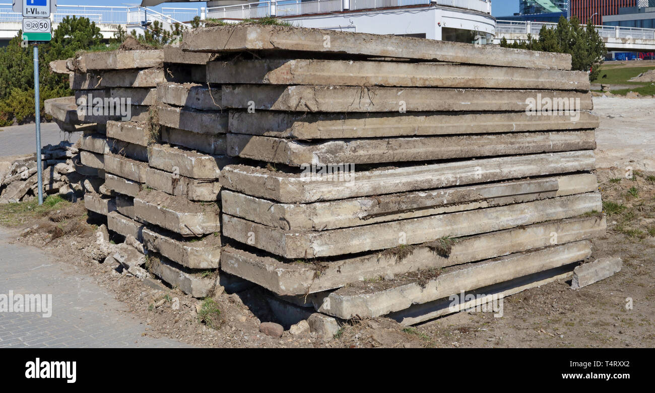 Old concrete slabs dug out of the ground and stacked. Construction site ...