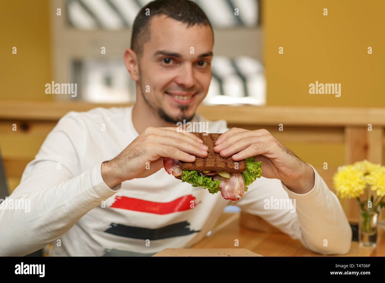 Hungry young man in resaurant eat sandwich Stock Photo - Alamy