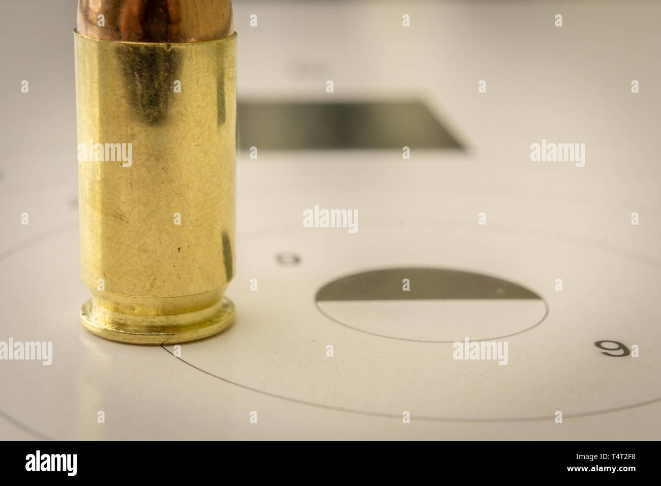 A 9mm bullet with a paper target in the background Stock Photo - Alamy
