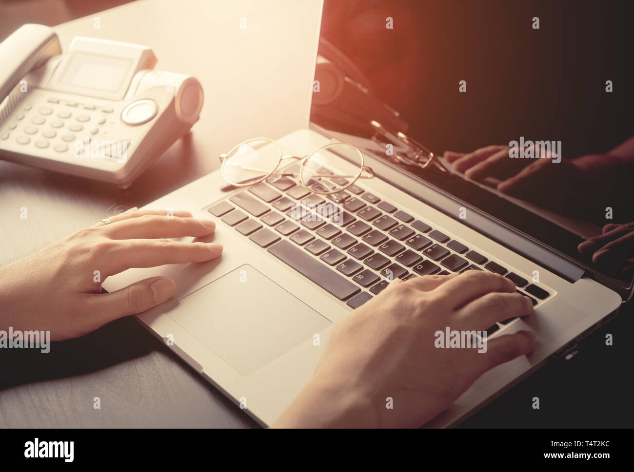 Hand on Laptop computer on sunny office desk with phone Stock Photo - Alamy