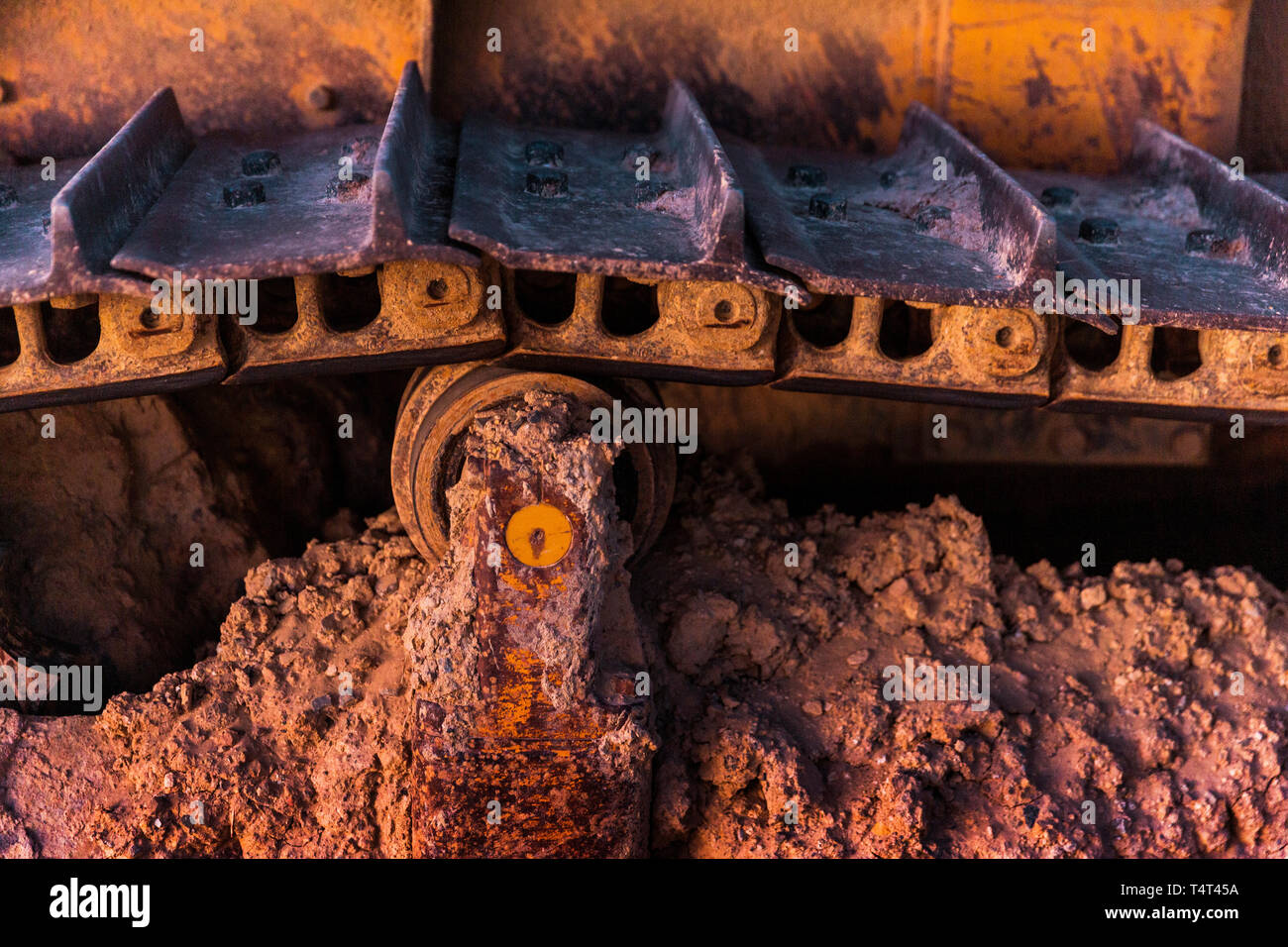 Dried mud stuck in old vintage yellow tractor with dusk natural light ...