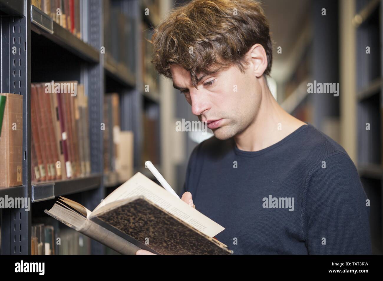 Student reading a book in library Stock Photo - Alamy