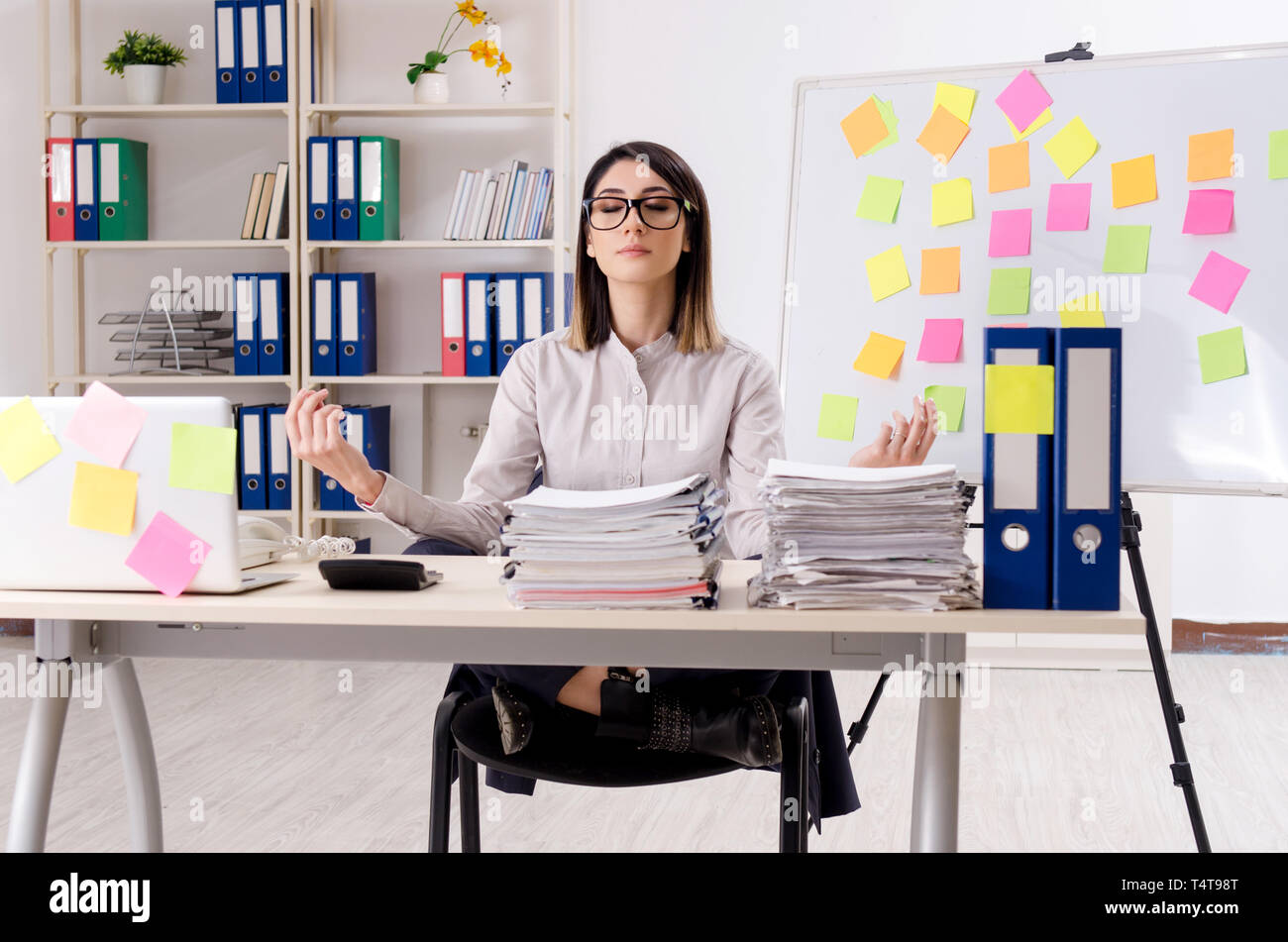 Young female employee doing exercises at workplace Stock Photo - Alamy