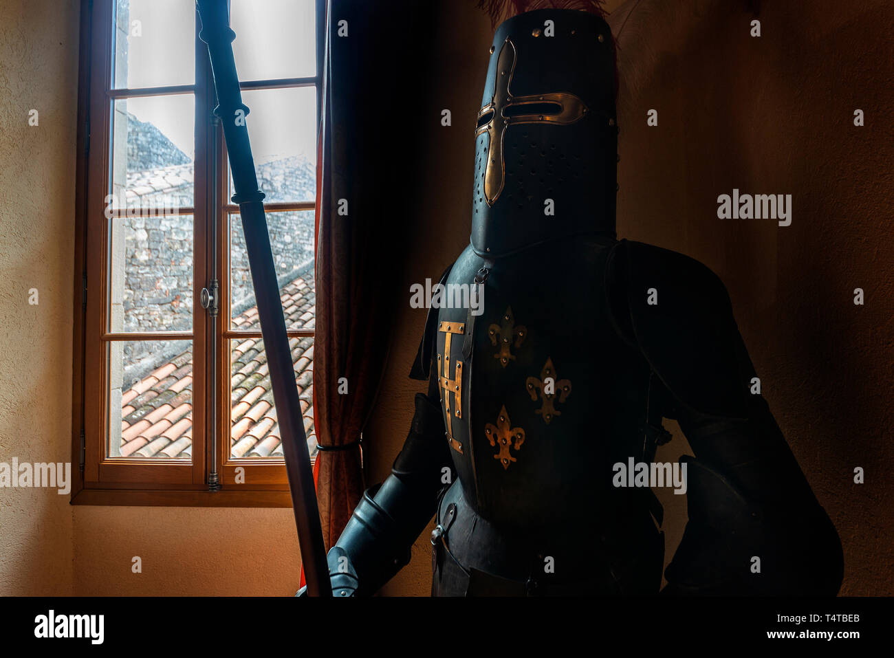 A partial view of a medieval knight in armour suit, illuminated by side ...