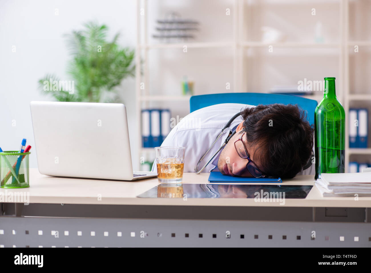 Young male doctor drinking in the office Stock Photo - Alamy