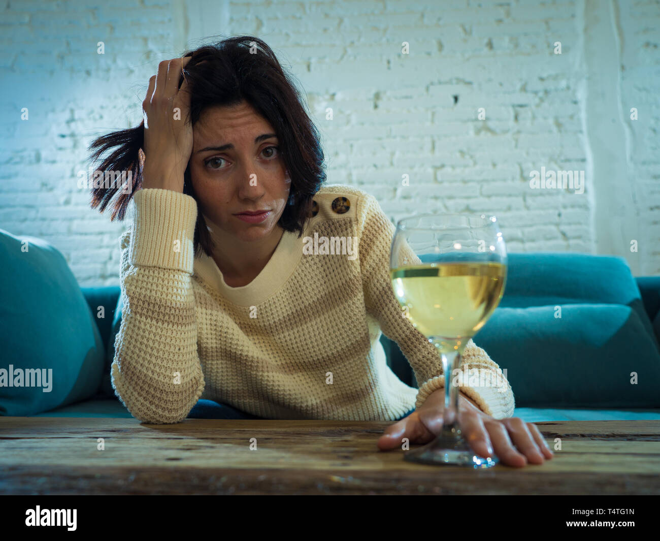 Stressed and hopeless young woman drinking a glass of wine alone at ...