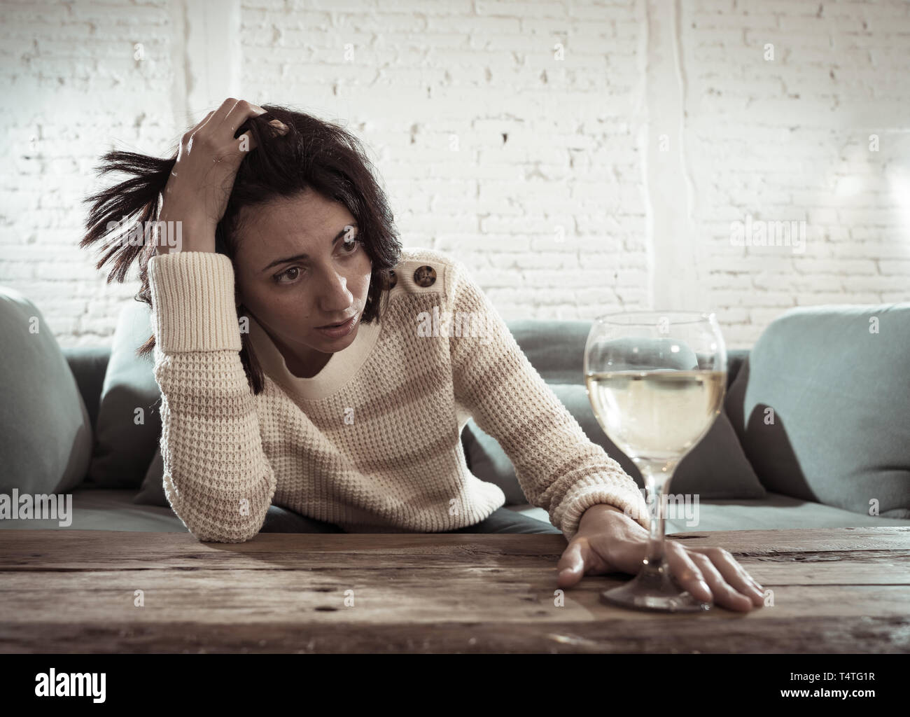 Stressed and hopeless young woman drinking a glass of wine alone at ...