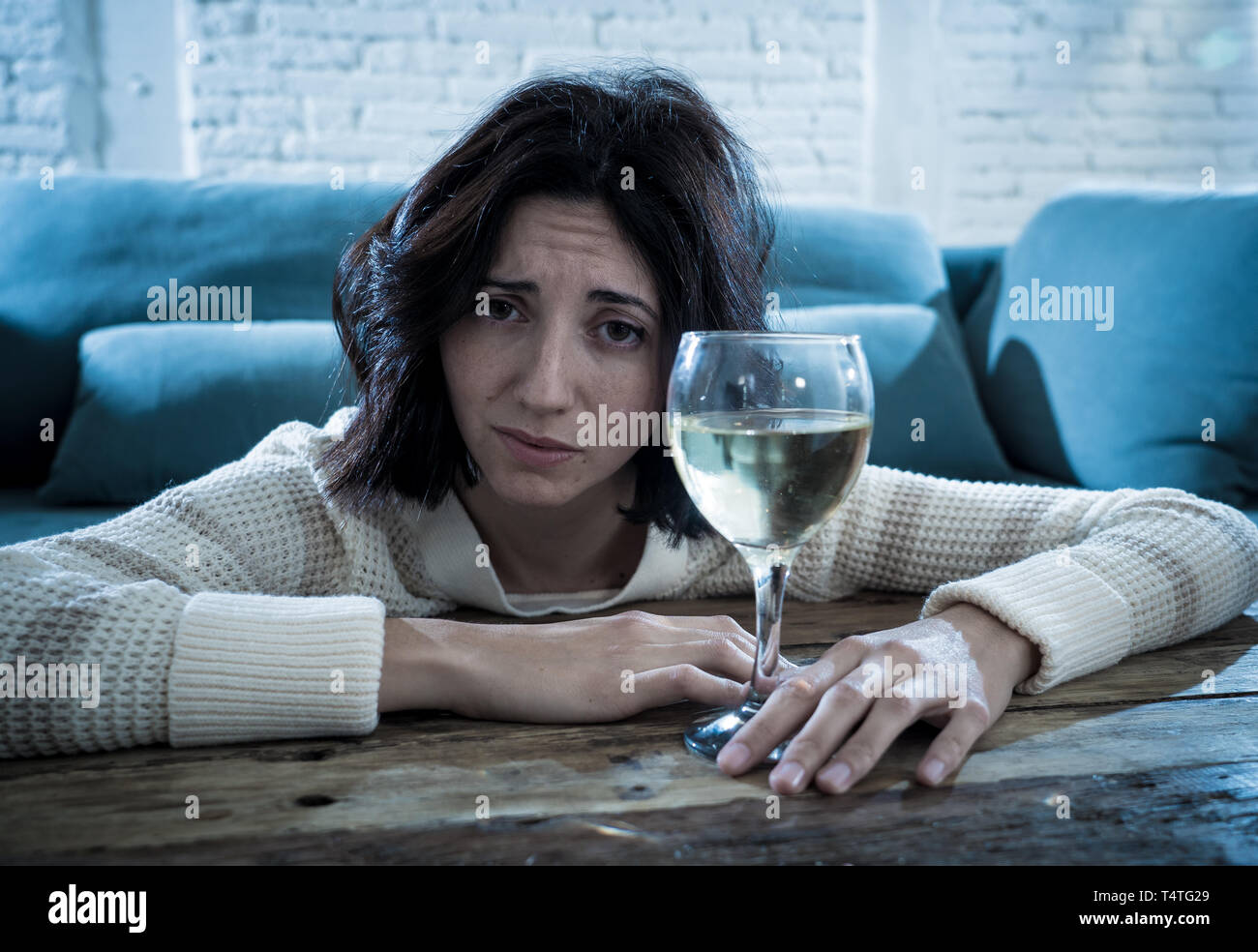 Stressed and hopeless young woman drinking a glass of wine alone at ...