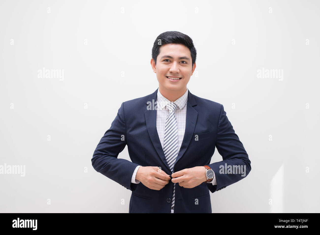 Waistup portrait of young smiling handsome businessman putting on suit ...