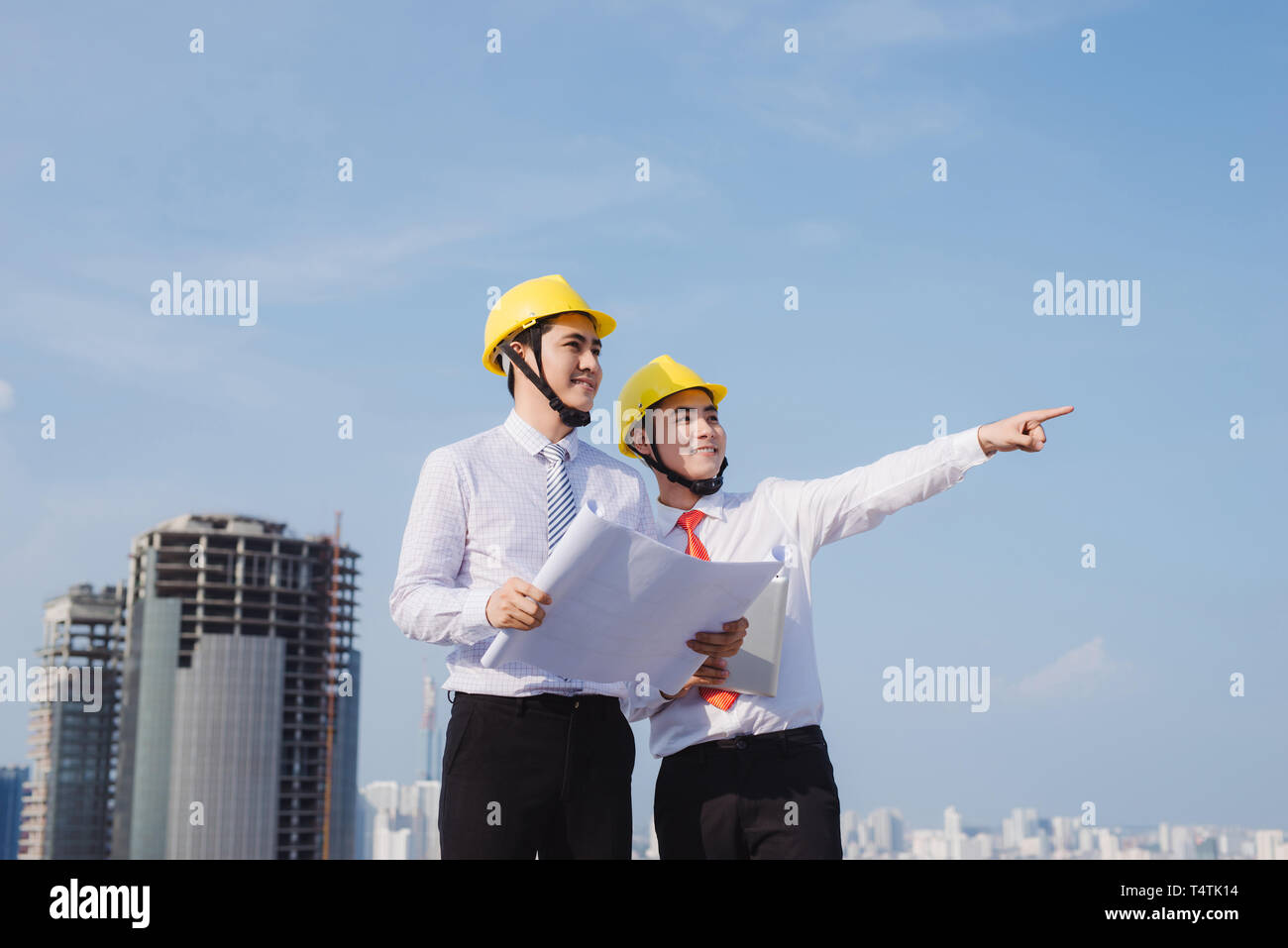 View of a Engineer and worker watching blueprint on construction site ...
