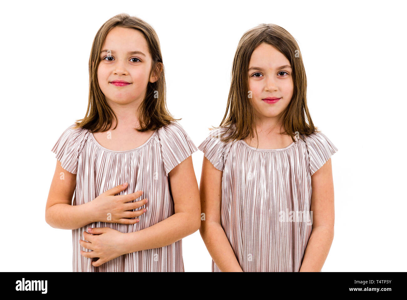 Identical twin girls sisters are posing for the camera. Happy twin ...