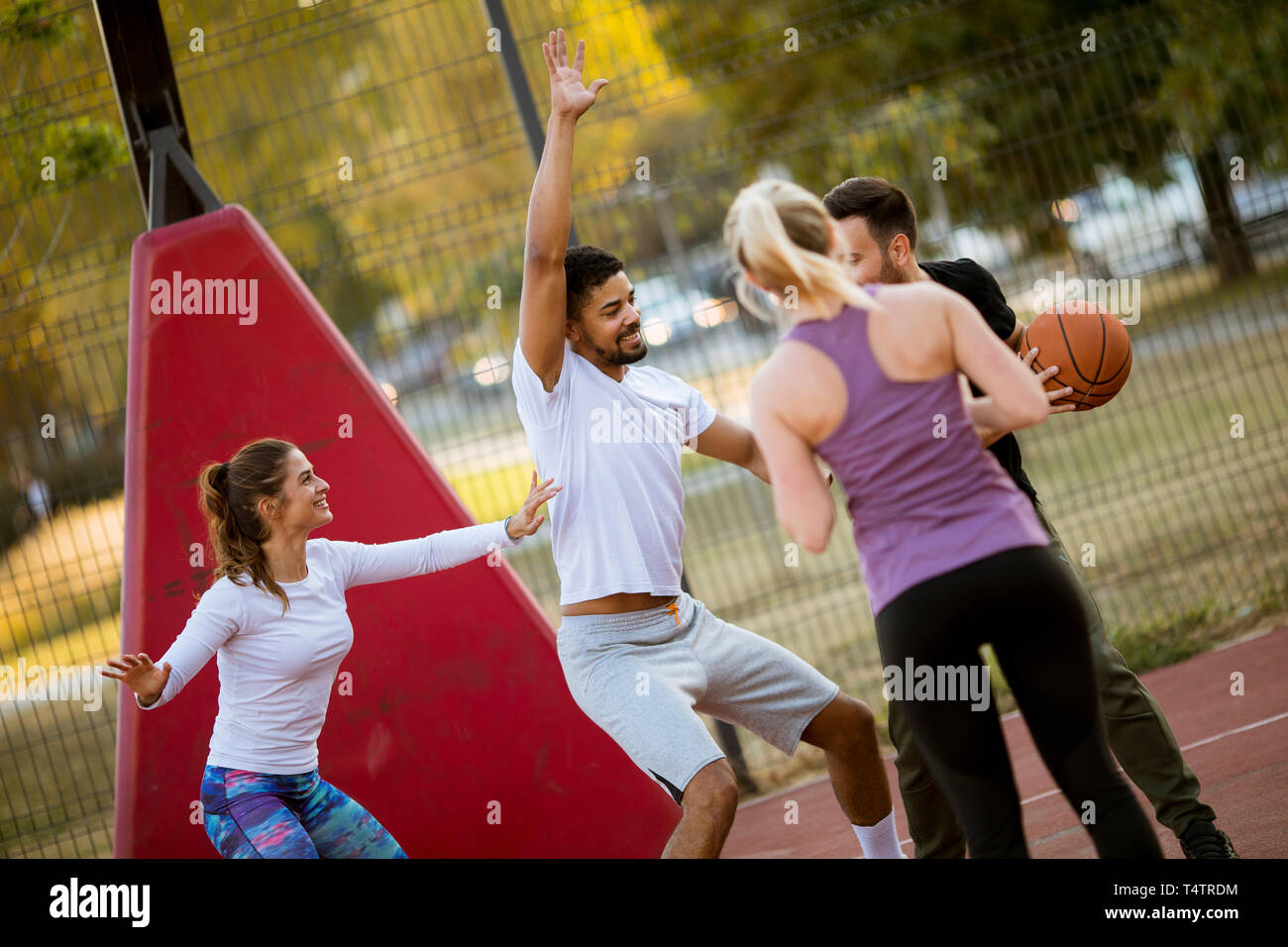 Group of multiracial young people playing basketball on court at ...