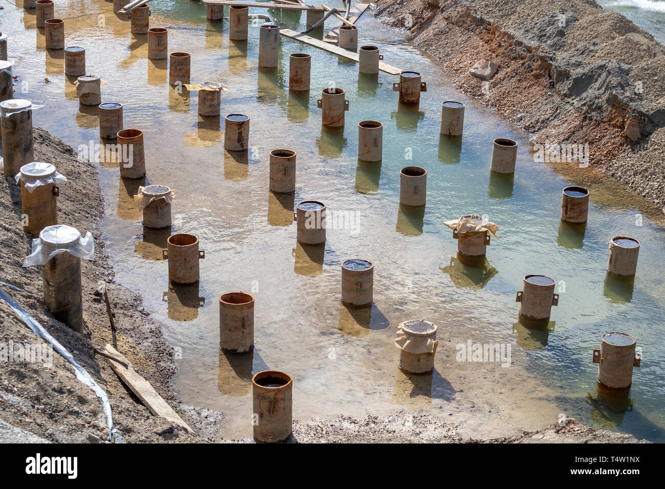 Row of construction piers on the river bank. Steel pillars for ...