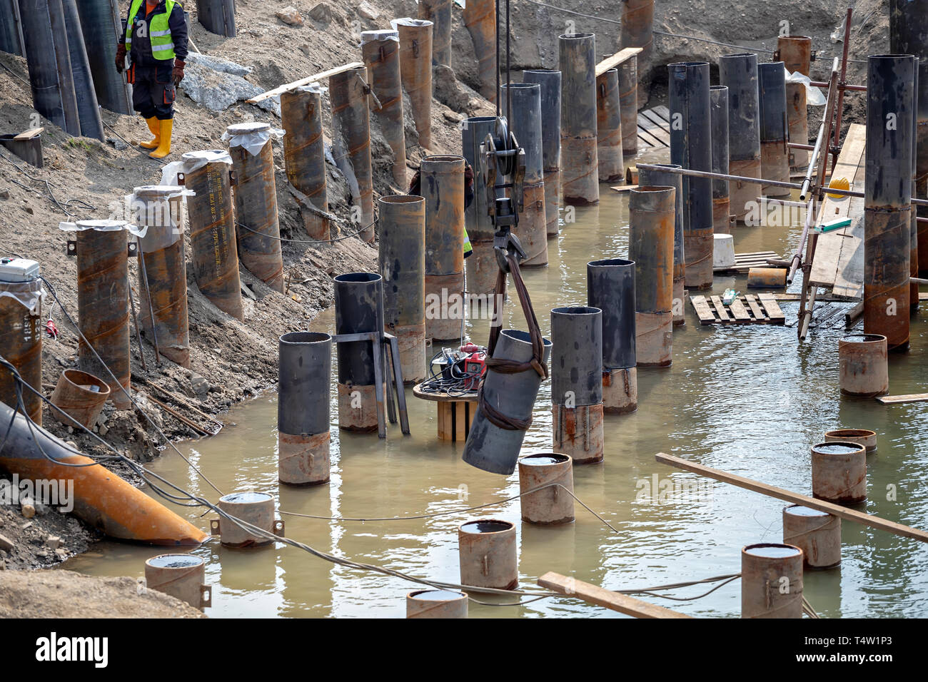 Row of construction poles on the river bank. Steel pillars for ...