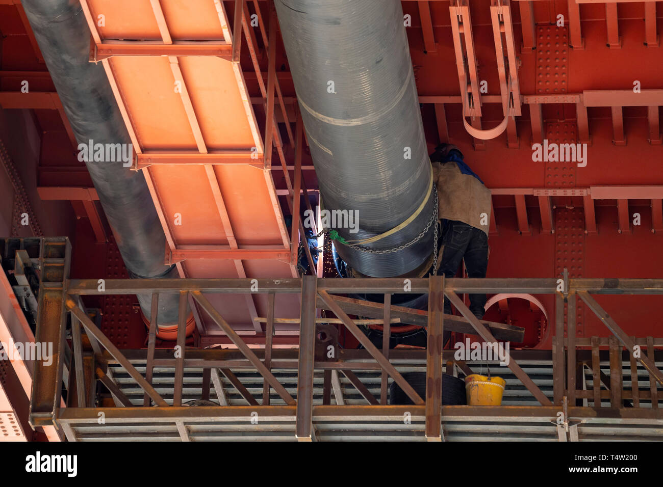 Welder workers welding pipes under metal bridge Stock Photo - Alamy