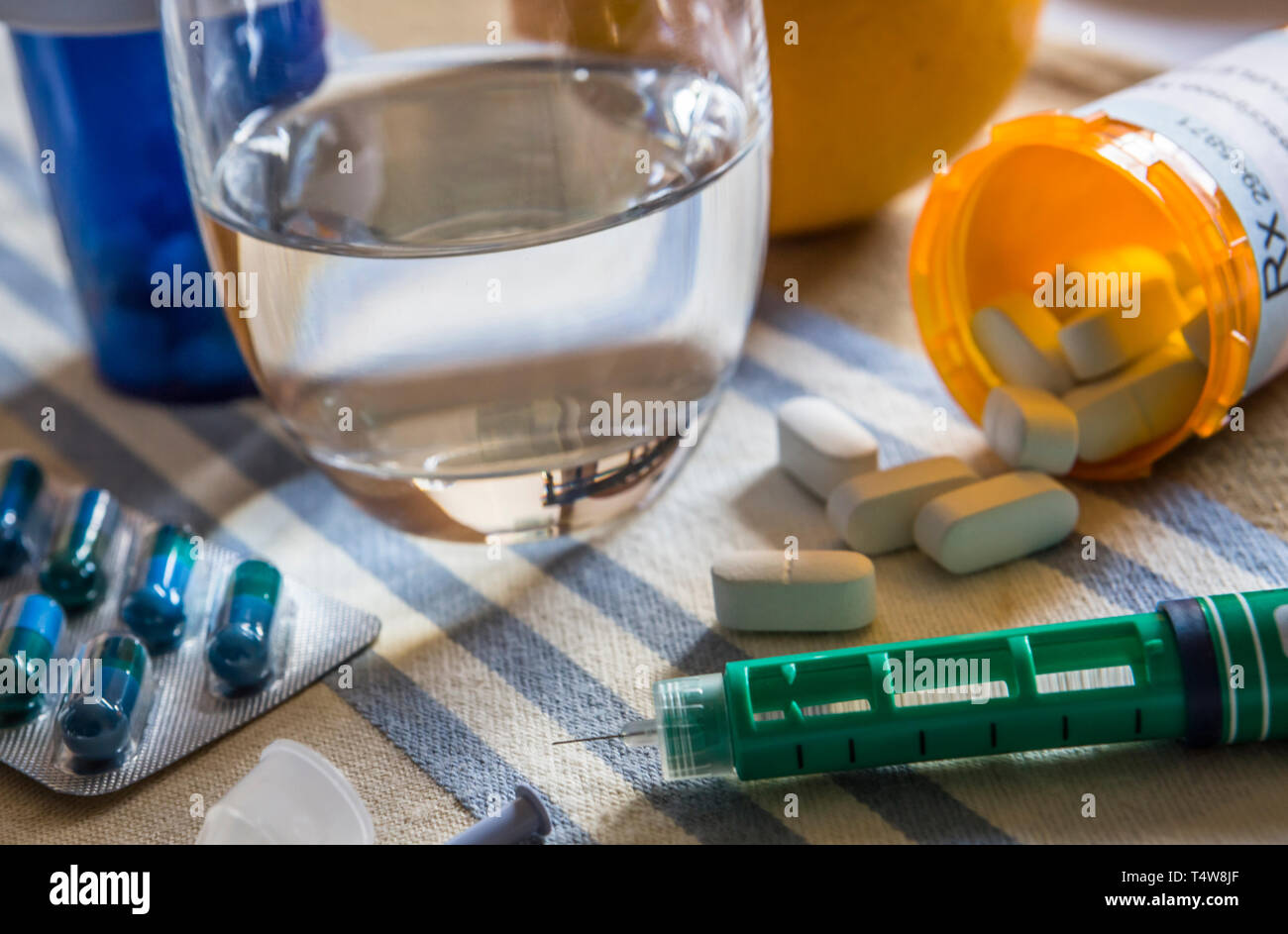 capsules next to a glass of water and Insulin injector, conceptual ...