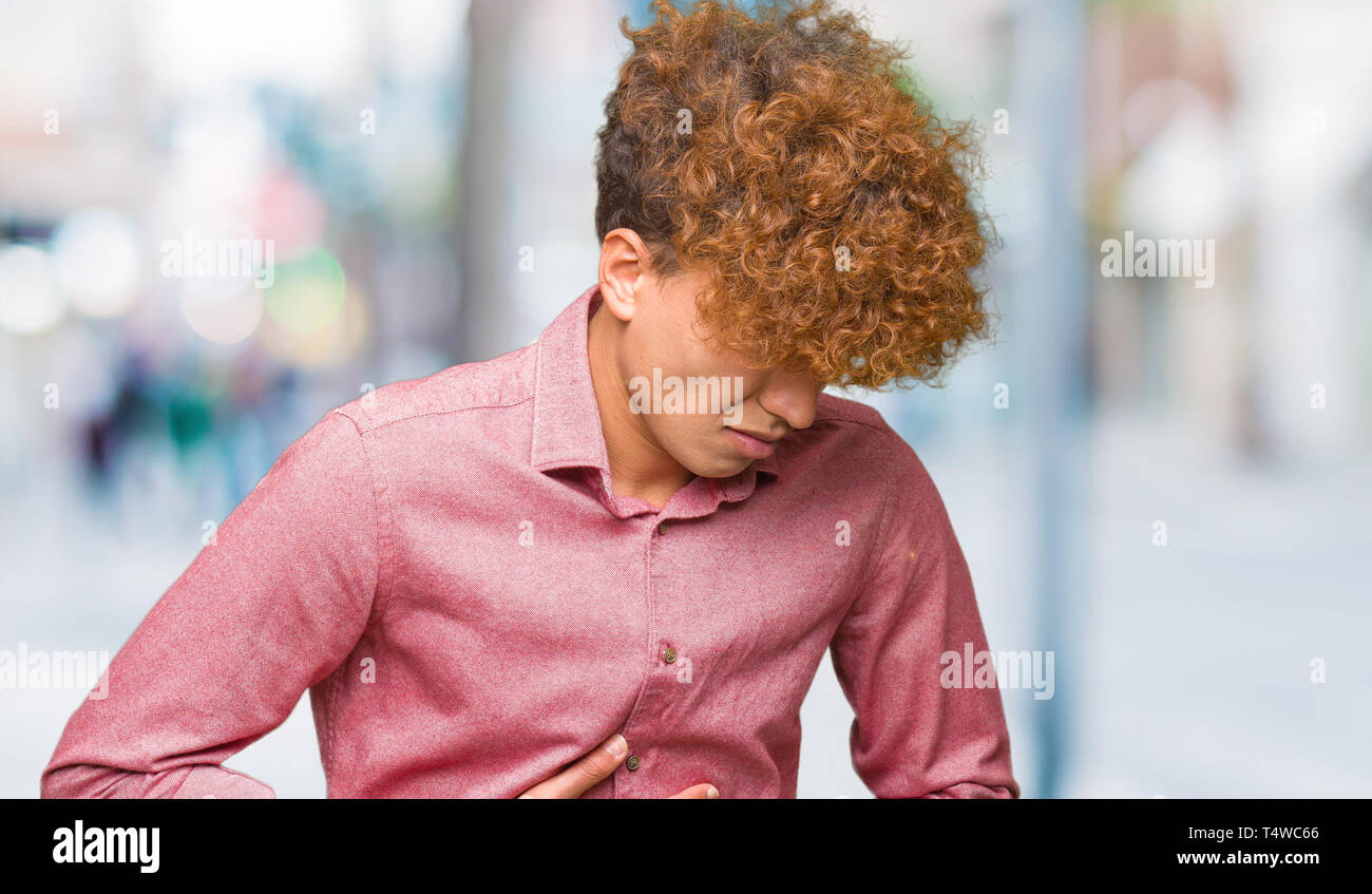 Young handsome business man with afro hair with hand on stomach because ...