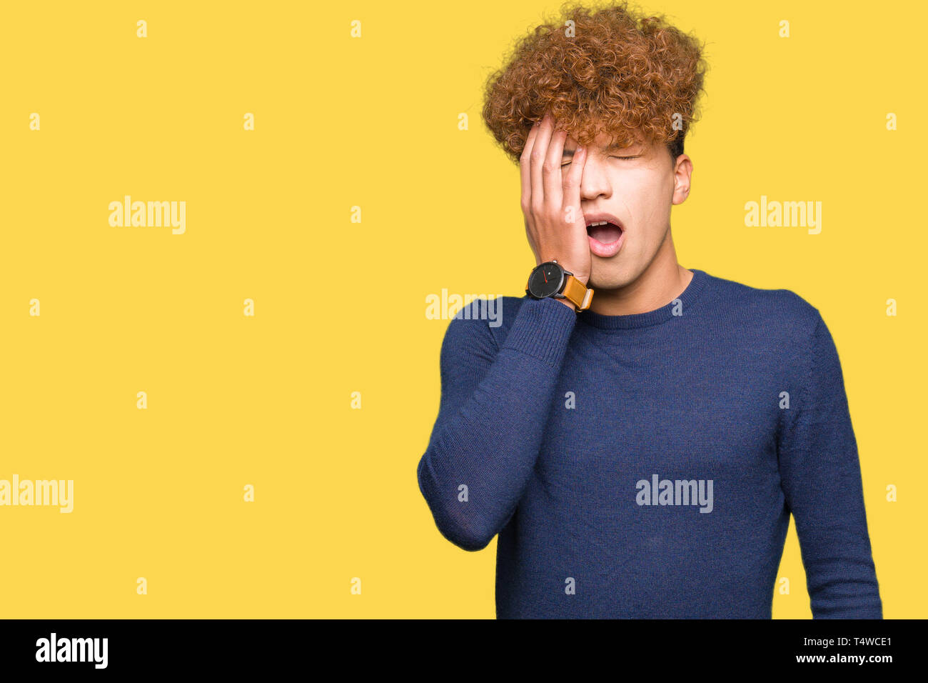 Young handsome man with afro hair Yawning tired covering half face, eye ...