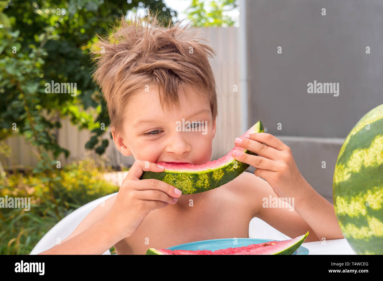 Beautiful kid eating watermelon outside in the garden. Red ripe ...