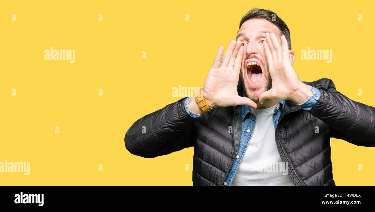 Handsome man wearing winter coat Shouting angry out loud with hands ...