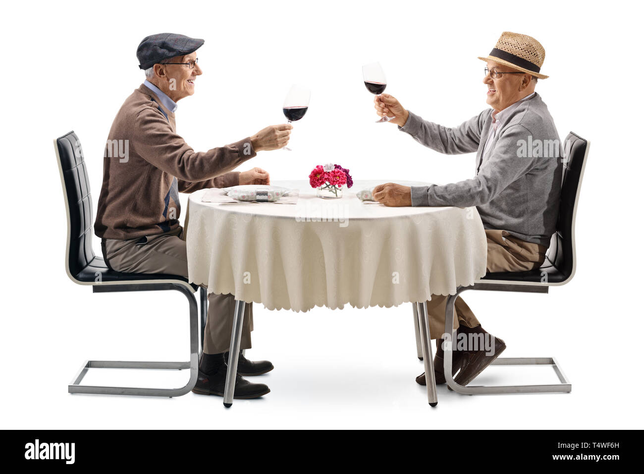 Elderly men toasting with red wine at a table isolated on white ...