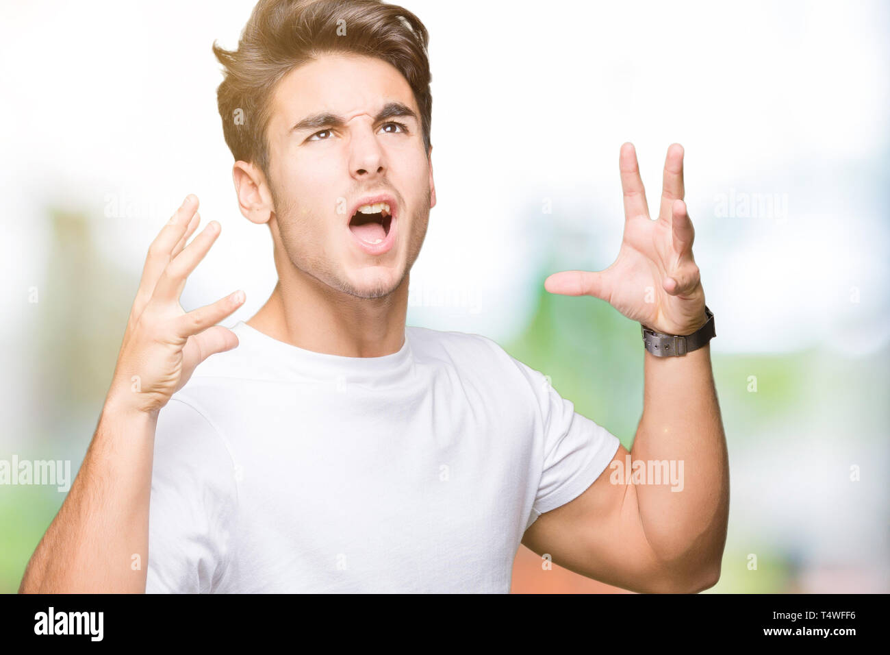 Young handsome man wearing white t-shirt over isolated background crazy ...
